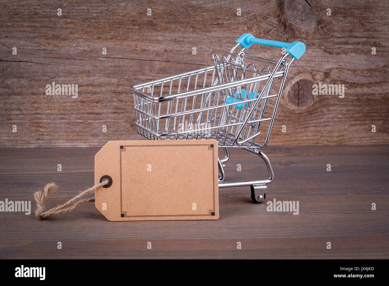 Purchasing cart with a blank price tag on a dark wooden background ...