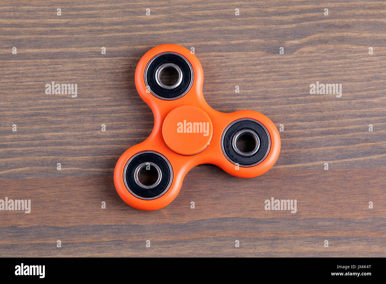 Orange fidget spinner stress relieving toy on wood background Stock ...