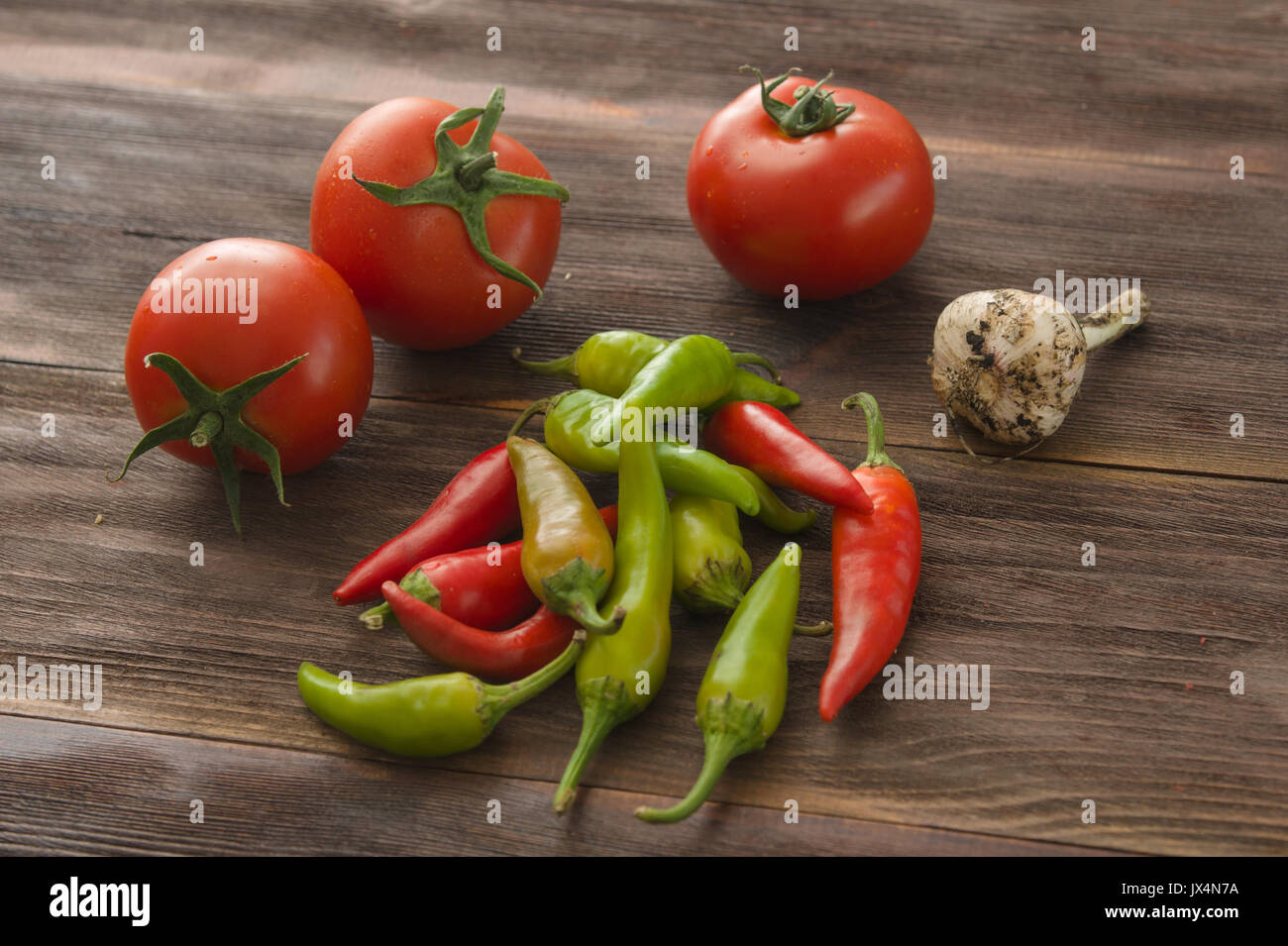 Ripe red tomatoes, hot chili peppers, garlic on a wooden table Stock ...