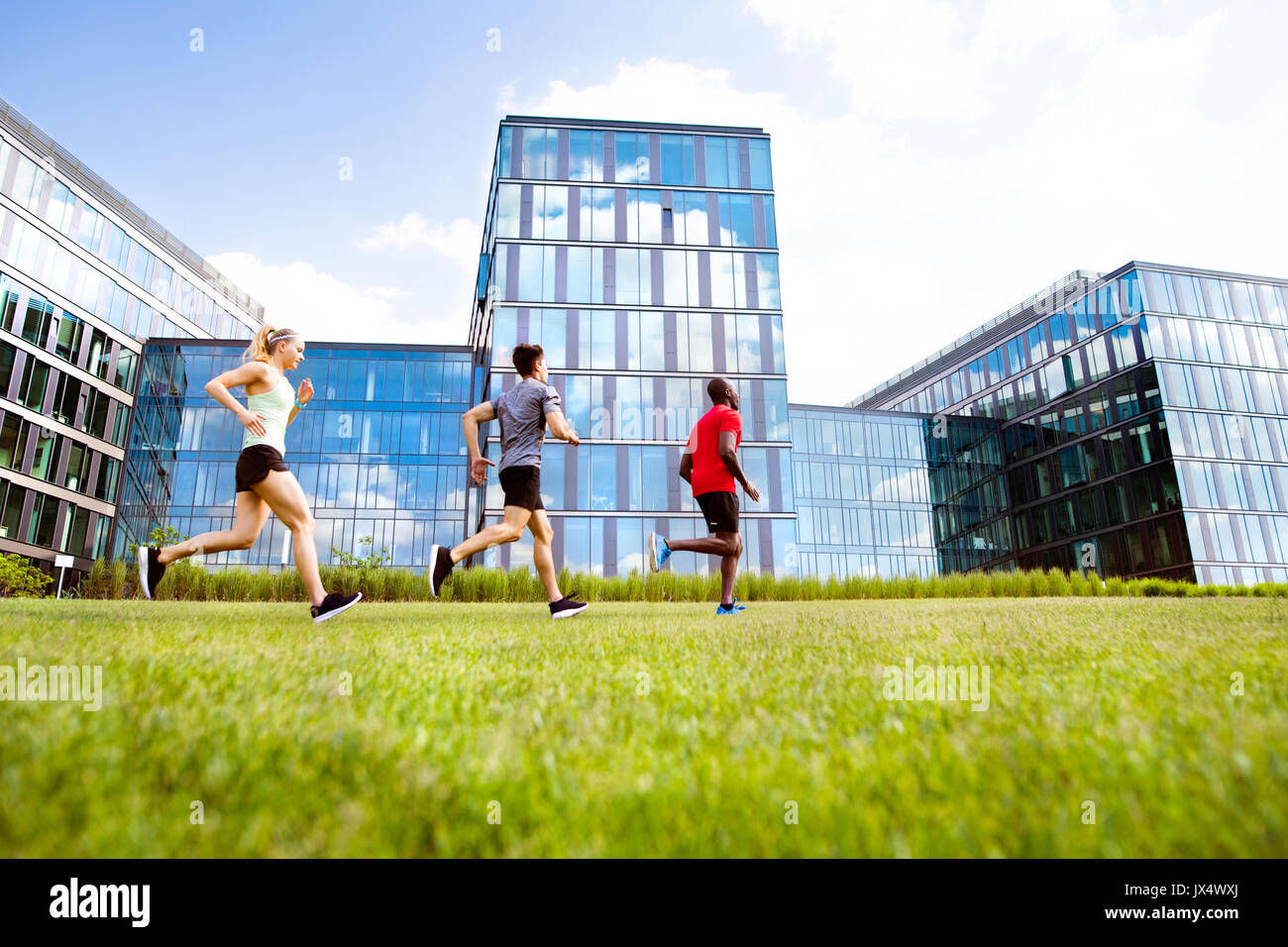 Beautiful young people running together in the city in front of glass ...