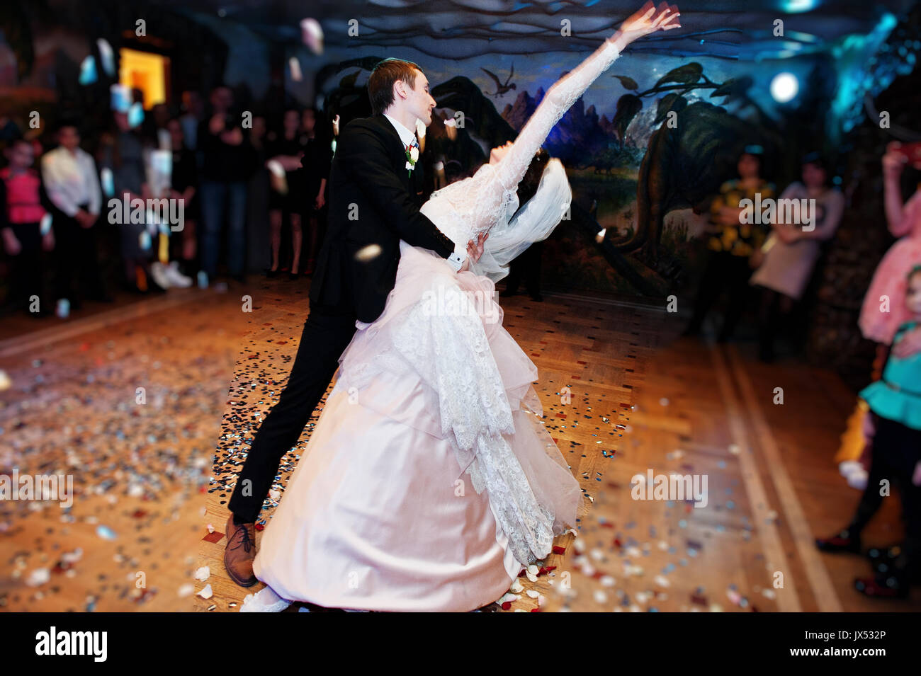 Wedding couple dancing their first dance in the restaurant with confetti on the floor Stock ...