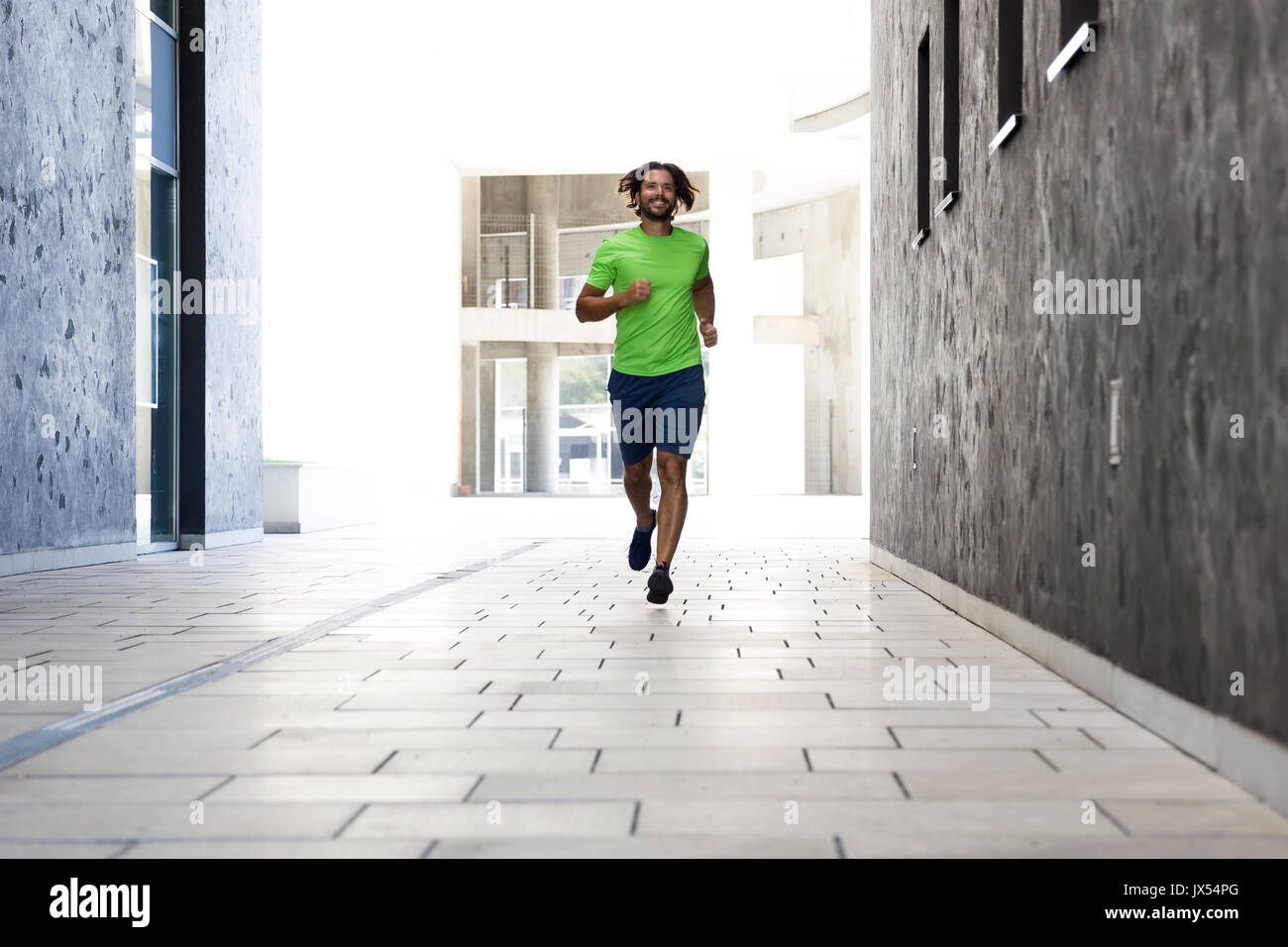 Young man running on the street in urban environment at sunny day Stock ...