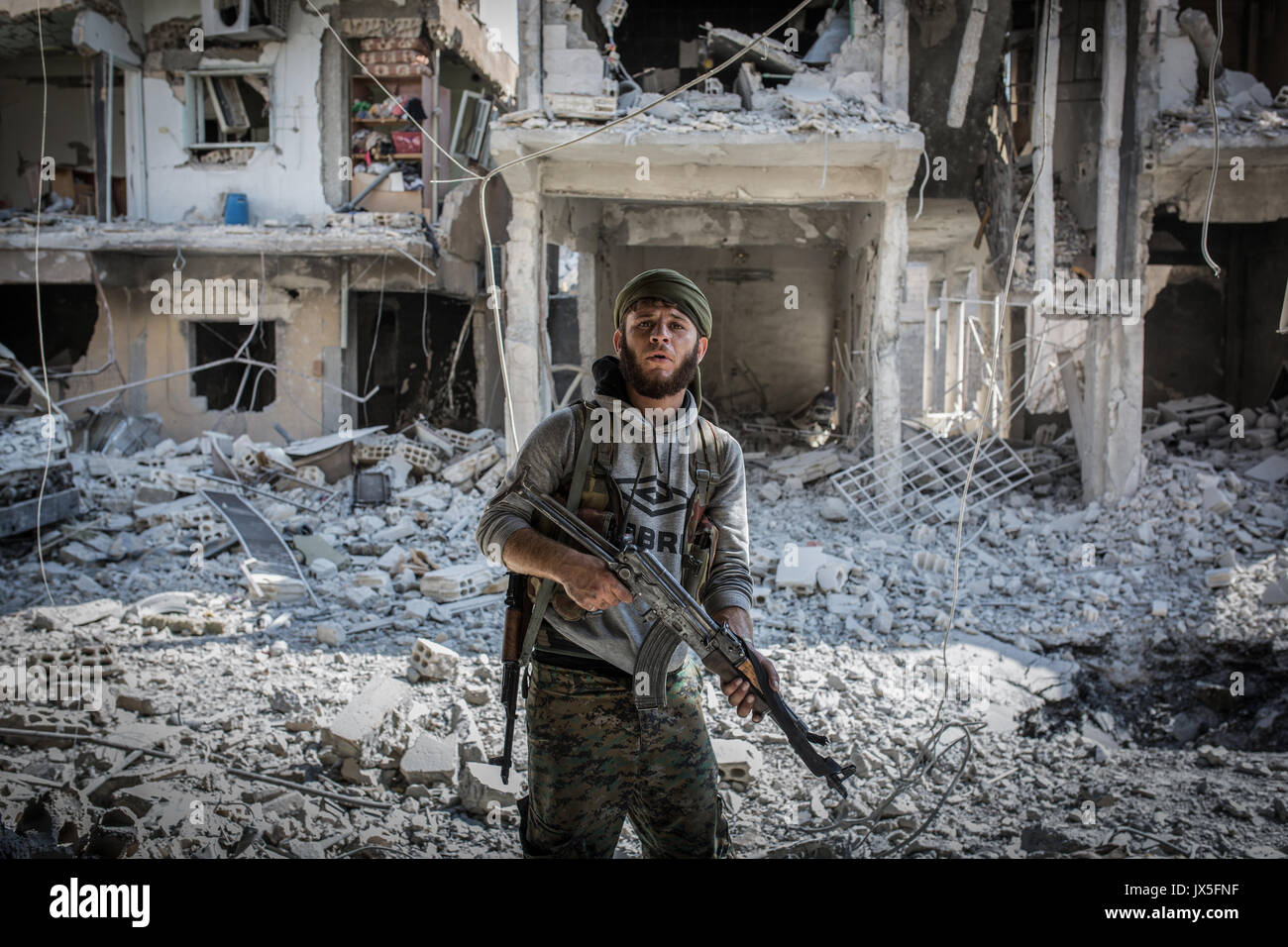 A soldier of the Syrian Democratic Forces (SDF) standing armed while ...
