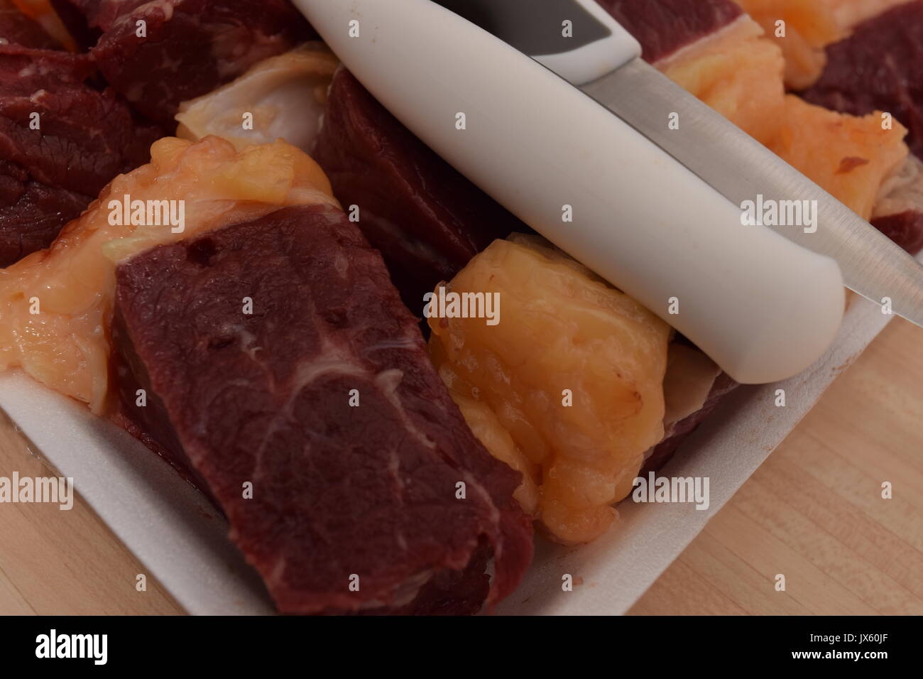 Side view of raw meat in pile with knives Stock Photo - Alamy