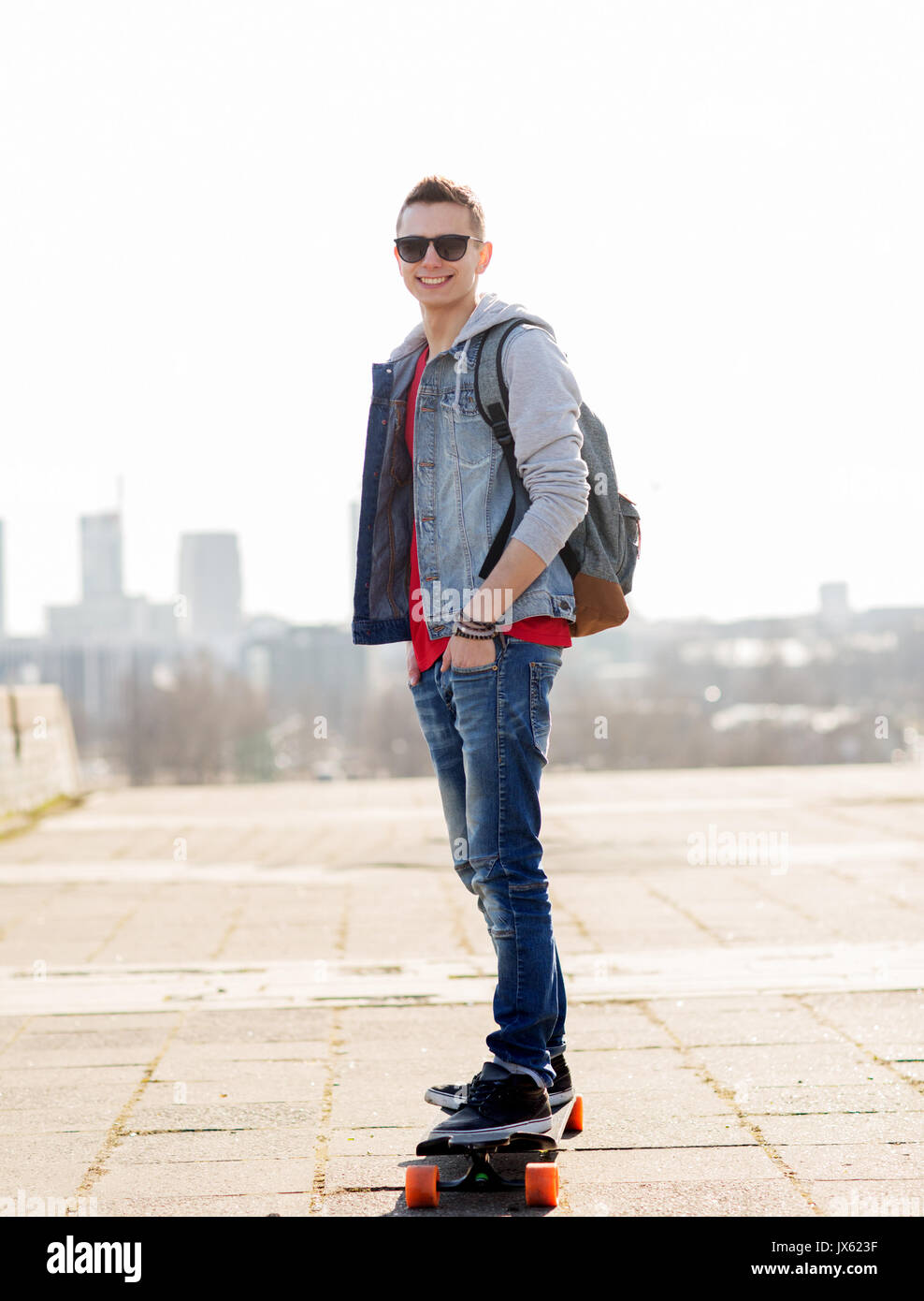 happy young man or teenage boy riding on longboard Stock Photo - Alamy