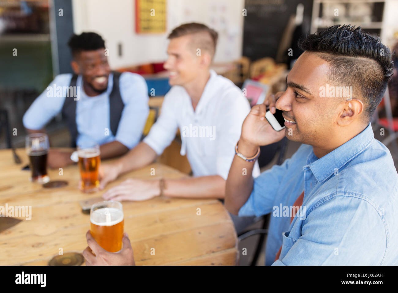 man calling on smartphone and drinking beer at bar Stock Photo - Alamy