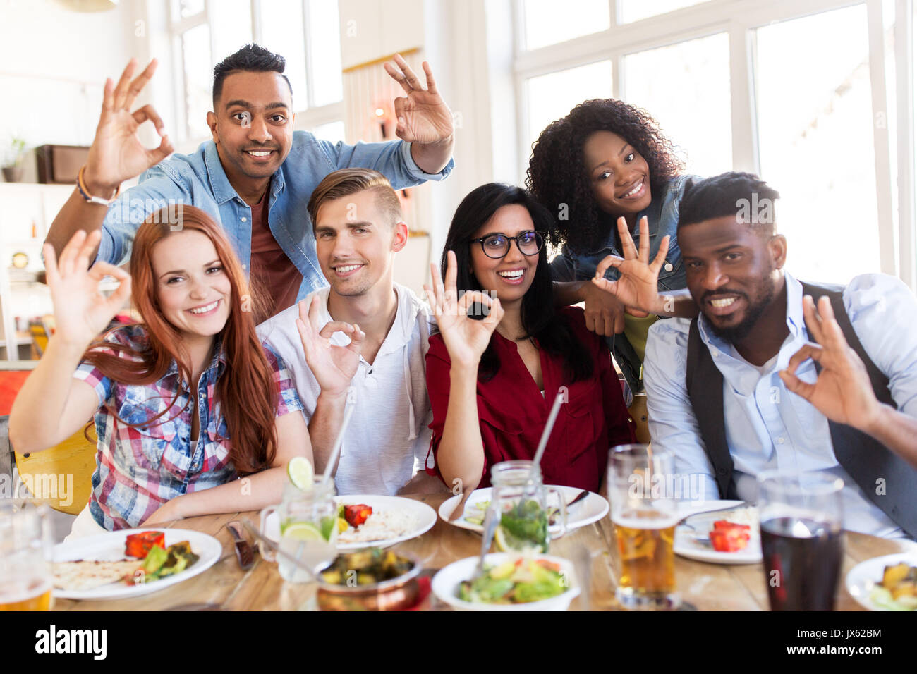 happy friends showing ok hand sign at restaurant Stock Photo - Alamy