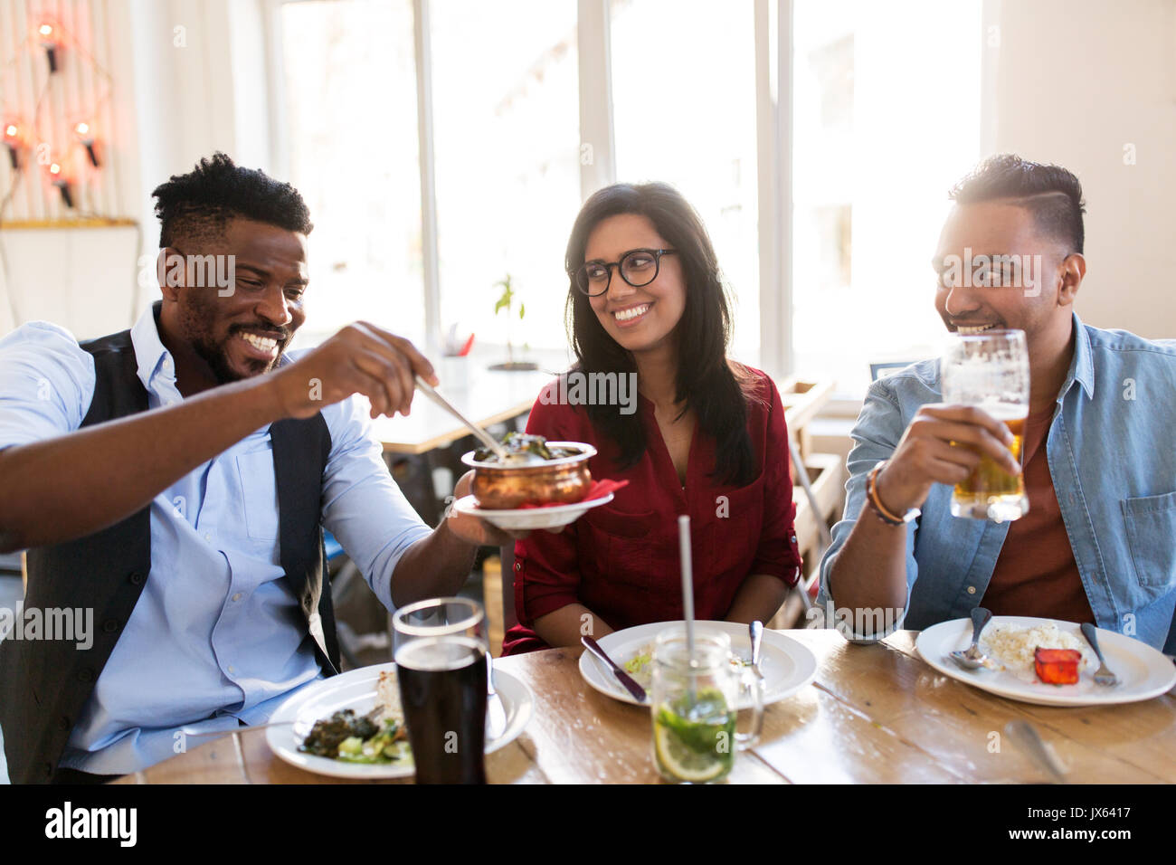 happy friends eating at restaurant Stock Photo - Alamy