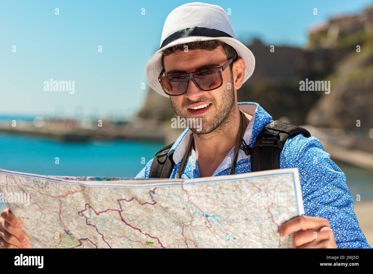 Portrait of a smiling tourist with map and bag Stock Photo - Alamy