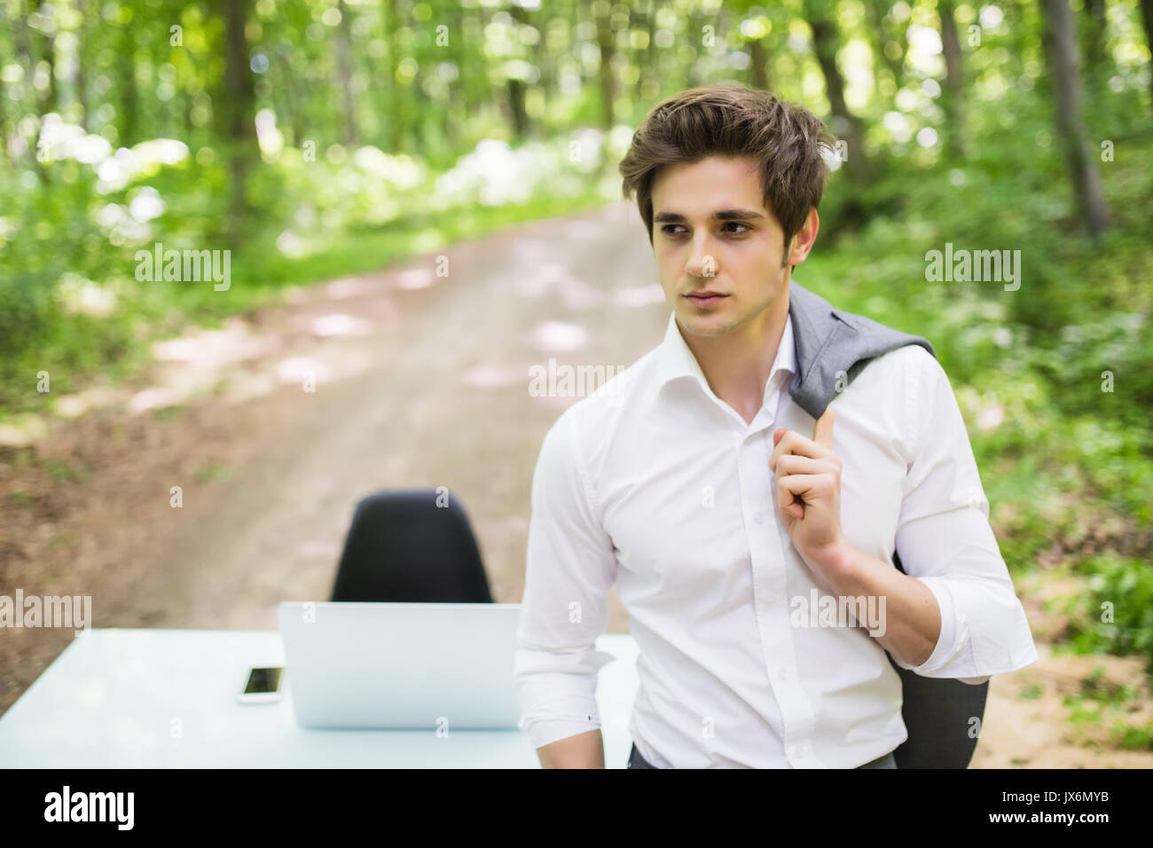 Handsome business man in suit in front of his office desk in green park ...