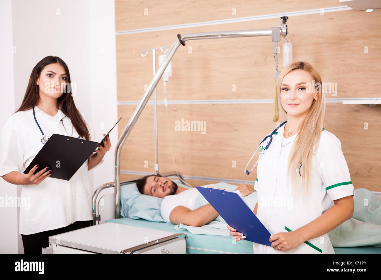 Patient in hospital room next to two nurses Stock Photo - Alamy