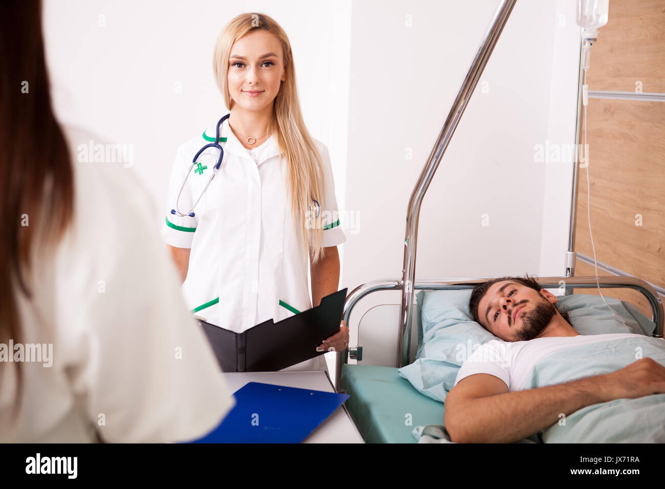 Patient in hospital room next to two nurses Stock Photo - Alamy