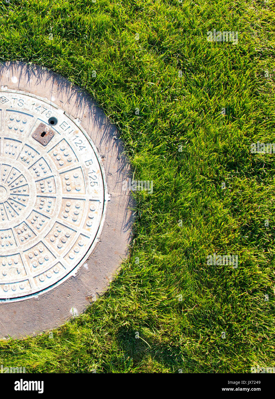 Metal manhole in a background of green grass on the field Stock Photo ...
