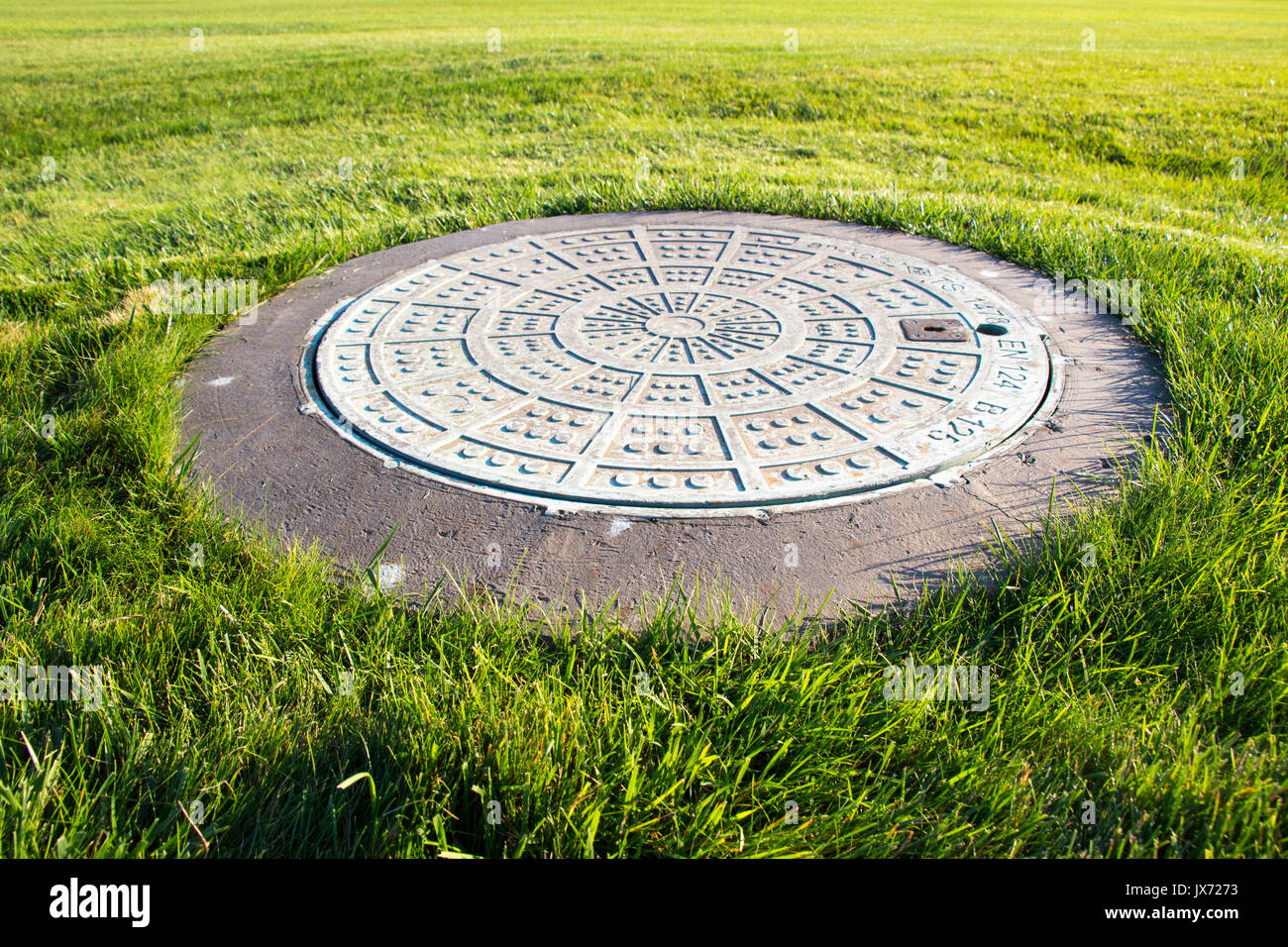 Metal manhole in a background of green grass on the field Stock Photo ...