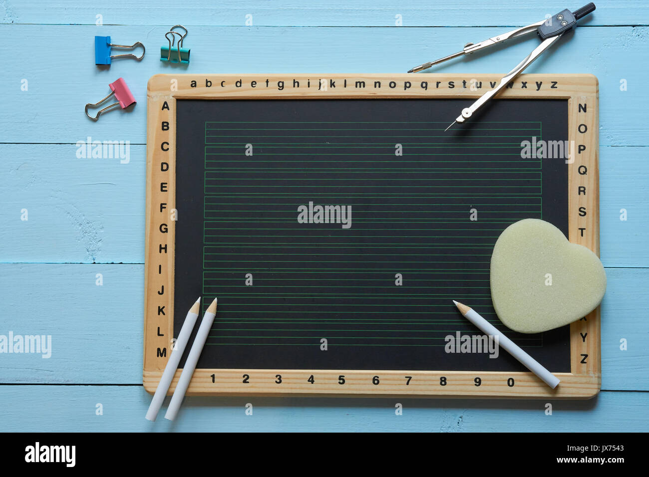 top shot of school lined chalkboard with numbers an letters on a desk ...