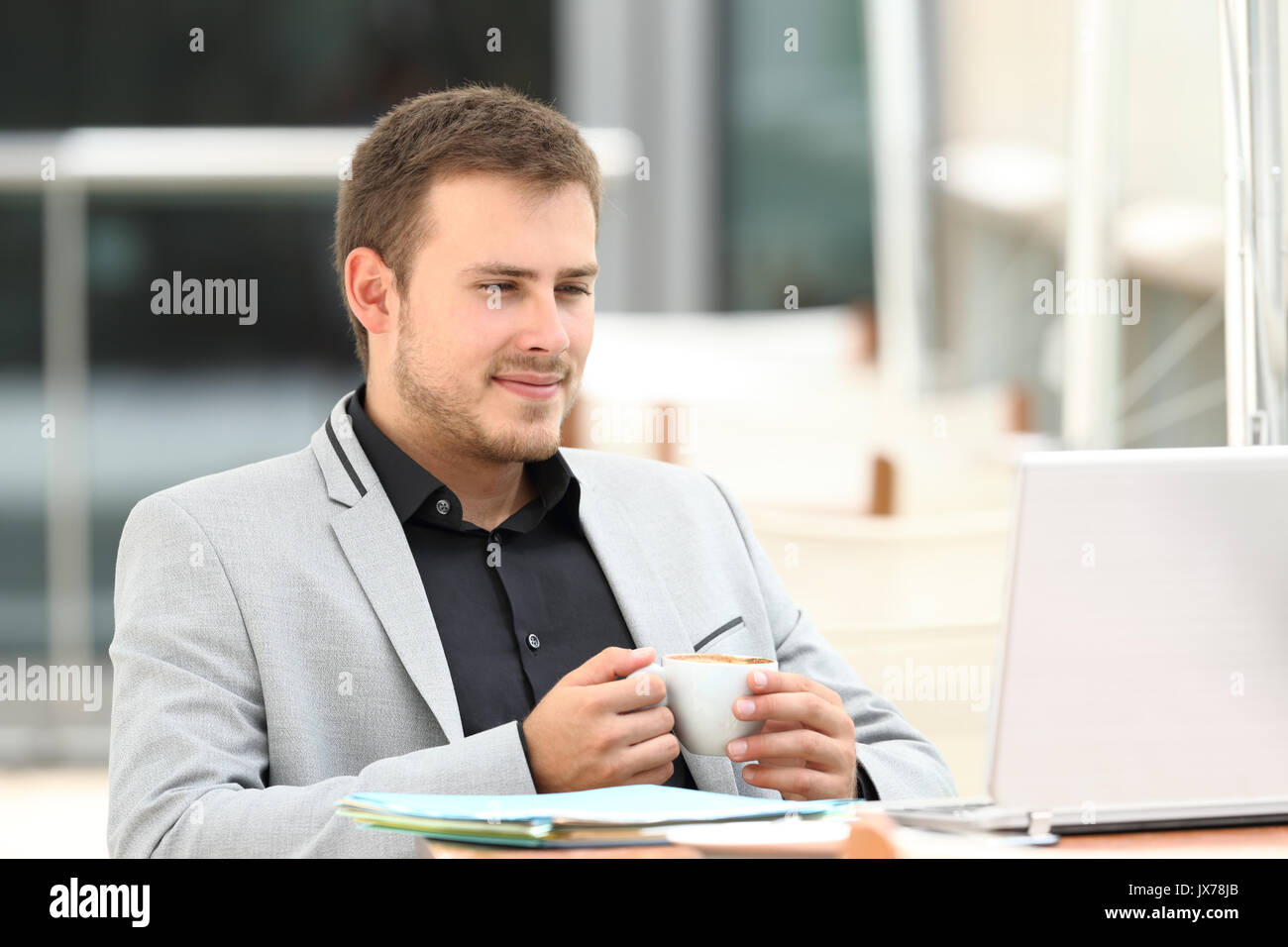 Executive reading on line content in a laptop sitting in a coffee shop ...