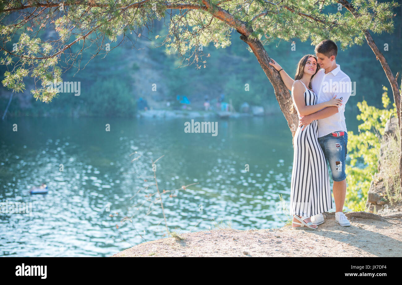Romantic couple standing on cliff over river. Lovely young couple going ...