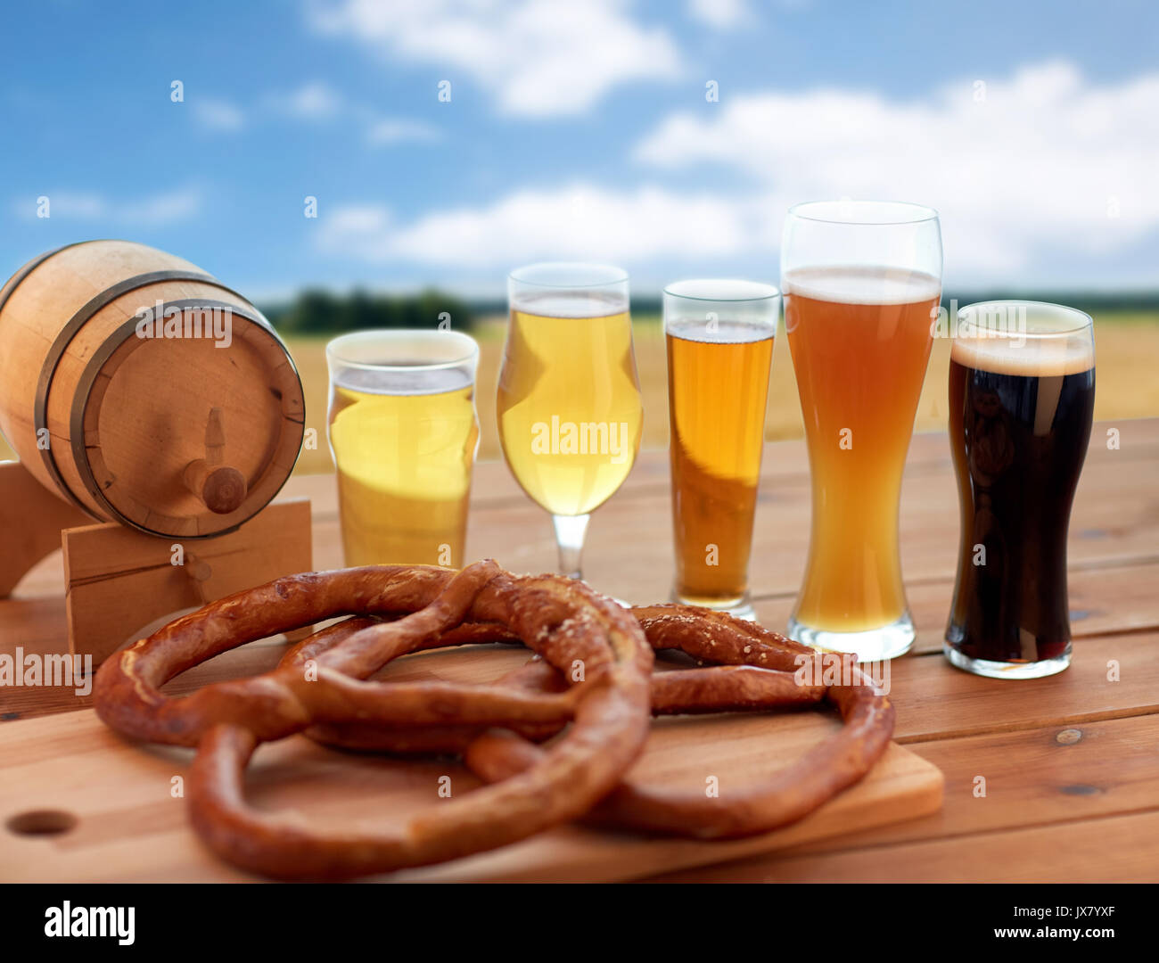 beer glasses, barrel and pretzel over cereal field Stock Photo - Alamy