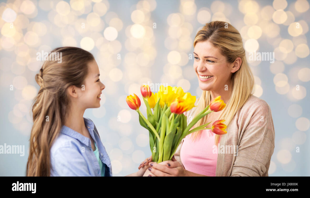 happy girl giving flowers to mother over lights Stock Photo - Alamy