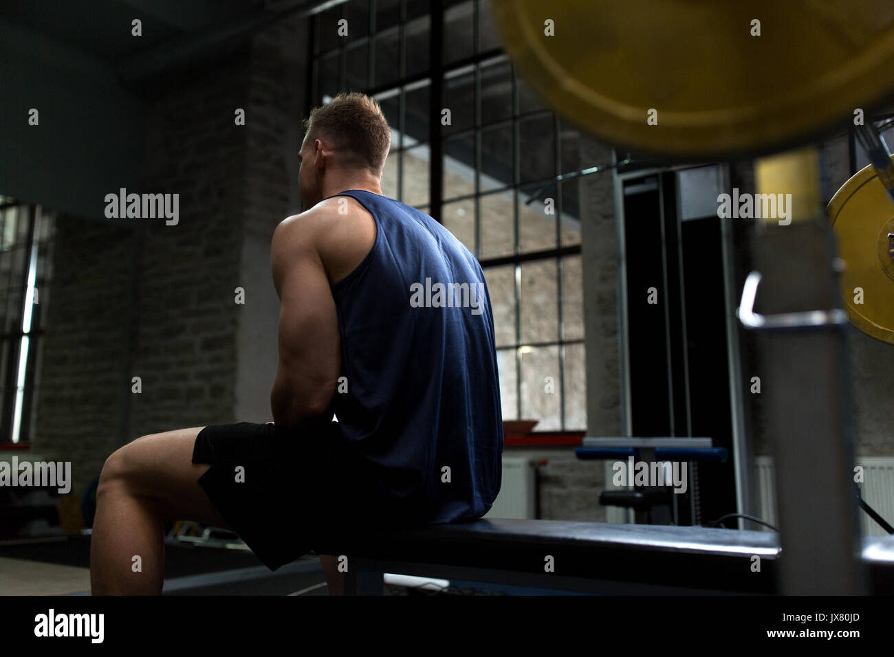 man sitting on weight bench in gym Stock Photo - Alamy