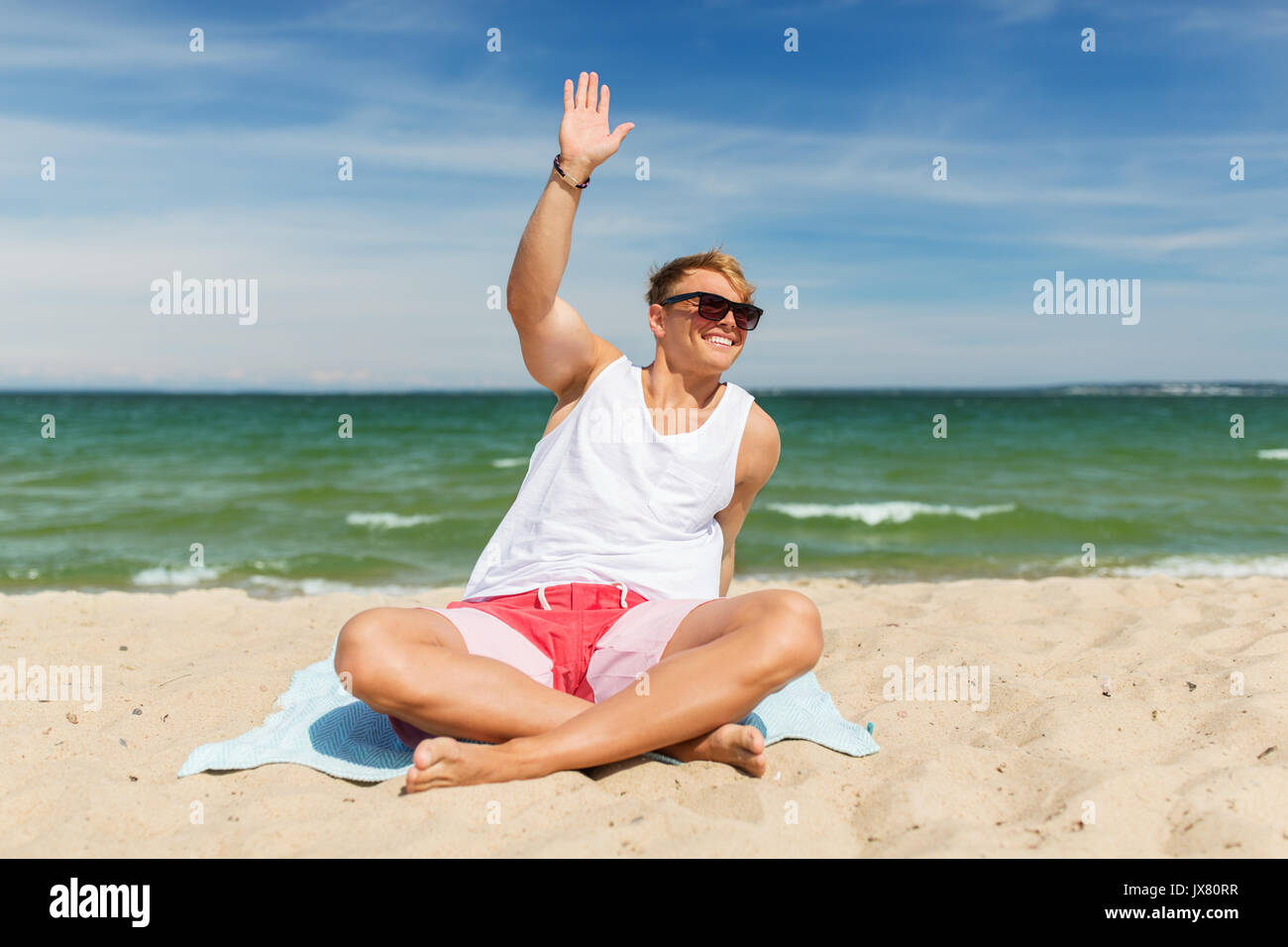 happy smiling young man sunbathing on beach towel Stock Photo - Alamy