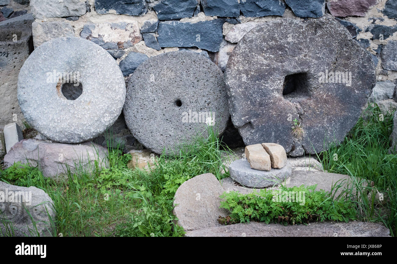 Stone granite wheels with rusted metal rim isolated on green grass near ...