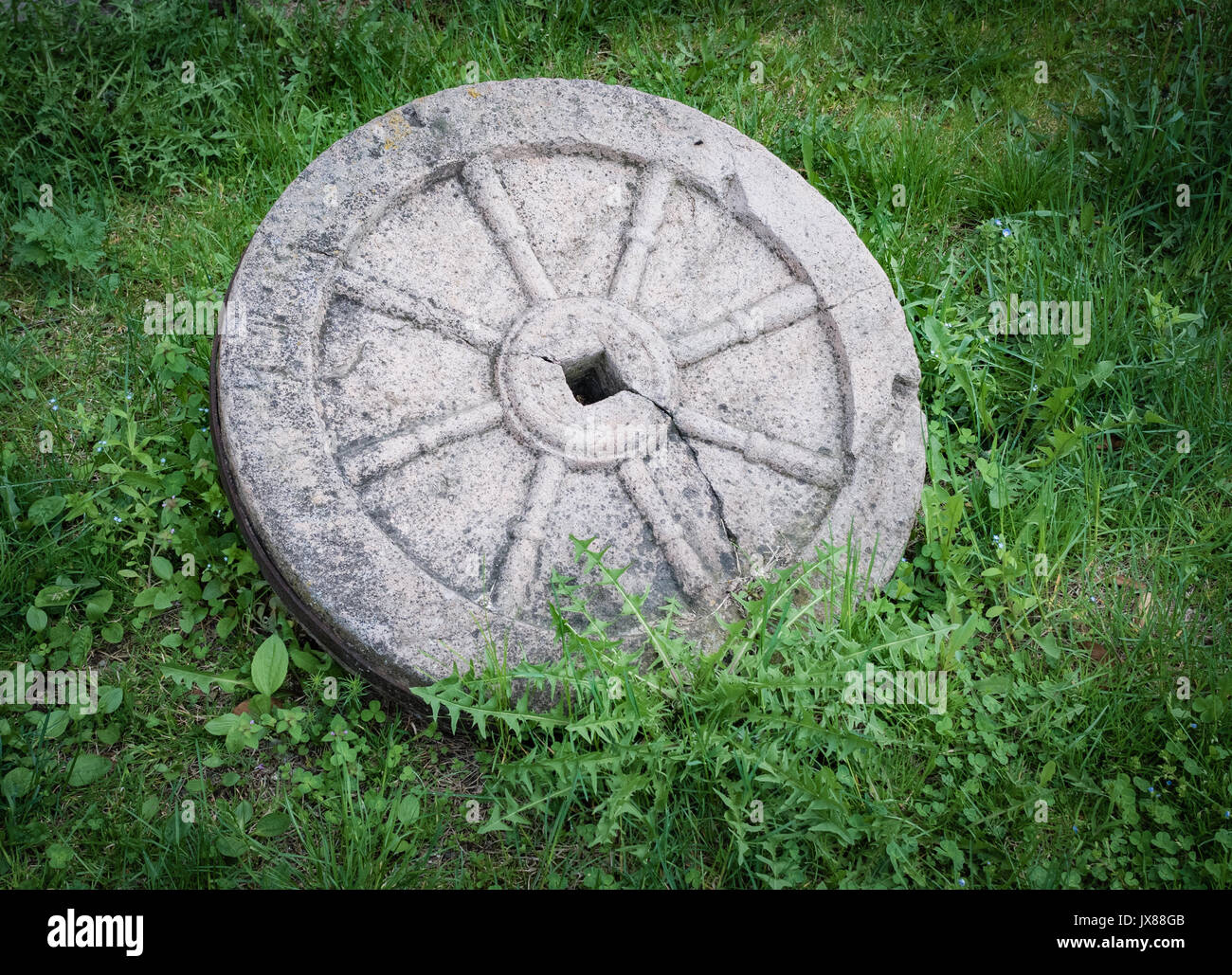 Stone granite wheel with rusted metal rim isolated on green grass Stock ...