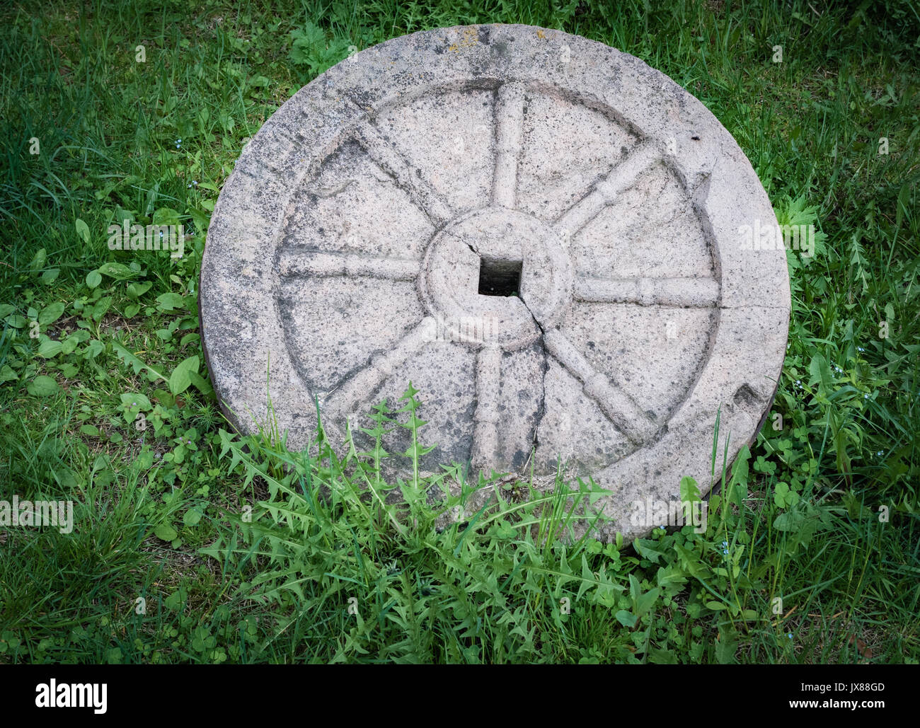 Stone granite wheel with rusted metal rim isolated on green grass Stock ...