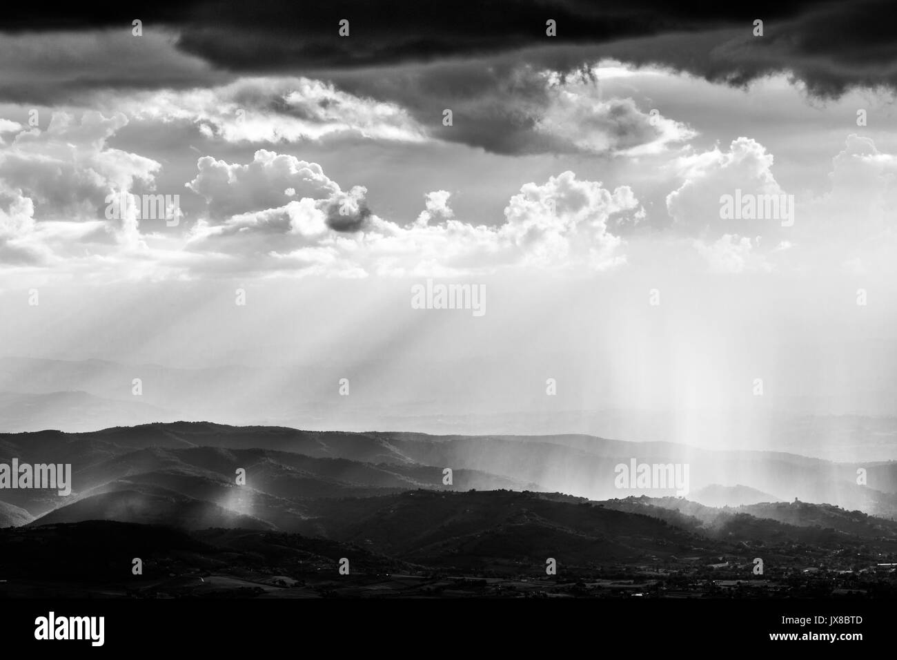 Spectacular view of sun rays and rain over some mountains and hills ...