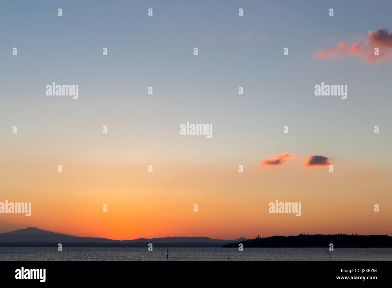 The end of sunset and the beginning of dusk on a lake, with big sky and ...
