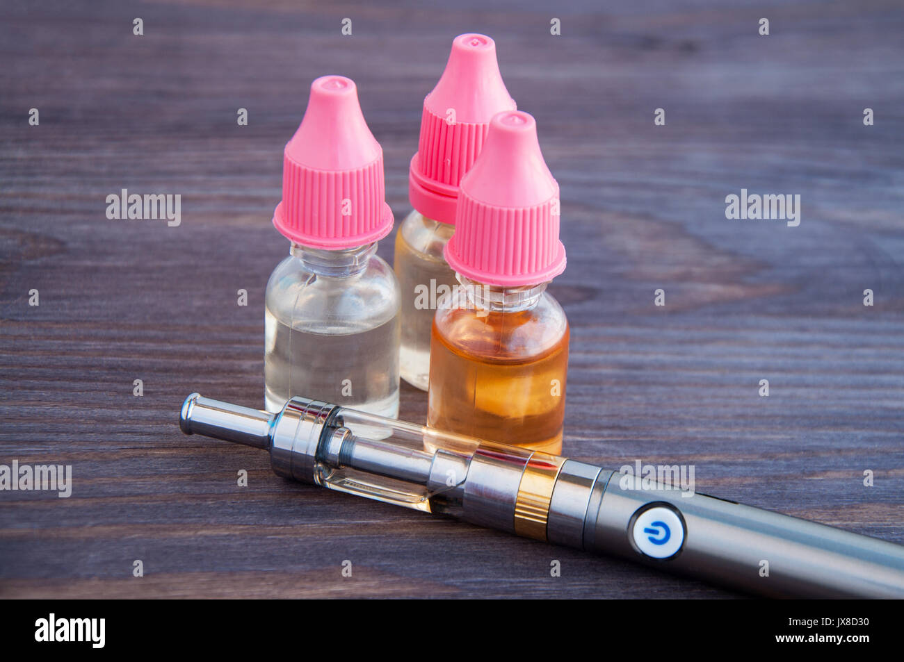 An electronic cigarette, a vape, and several bottles of liquid for ...