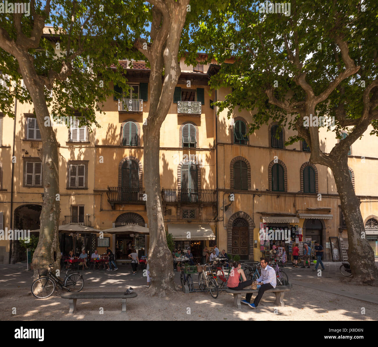 People relax in the shade of the plane trees on the Piazza Napoleone of ...