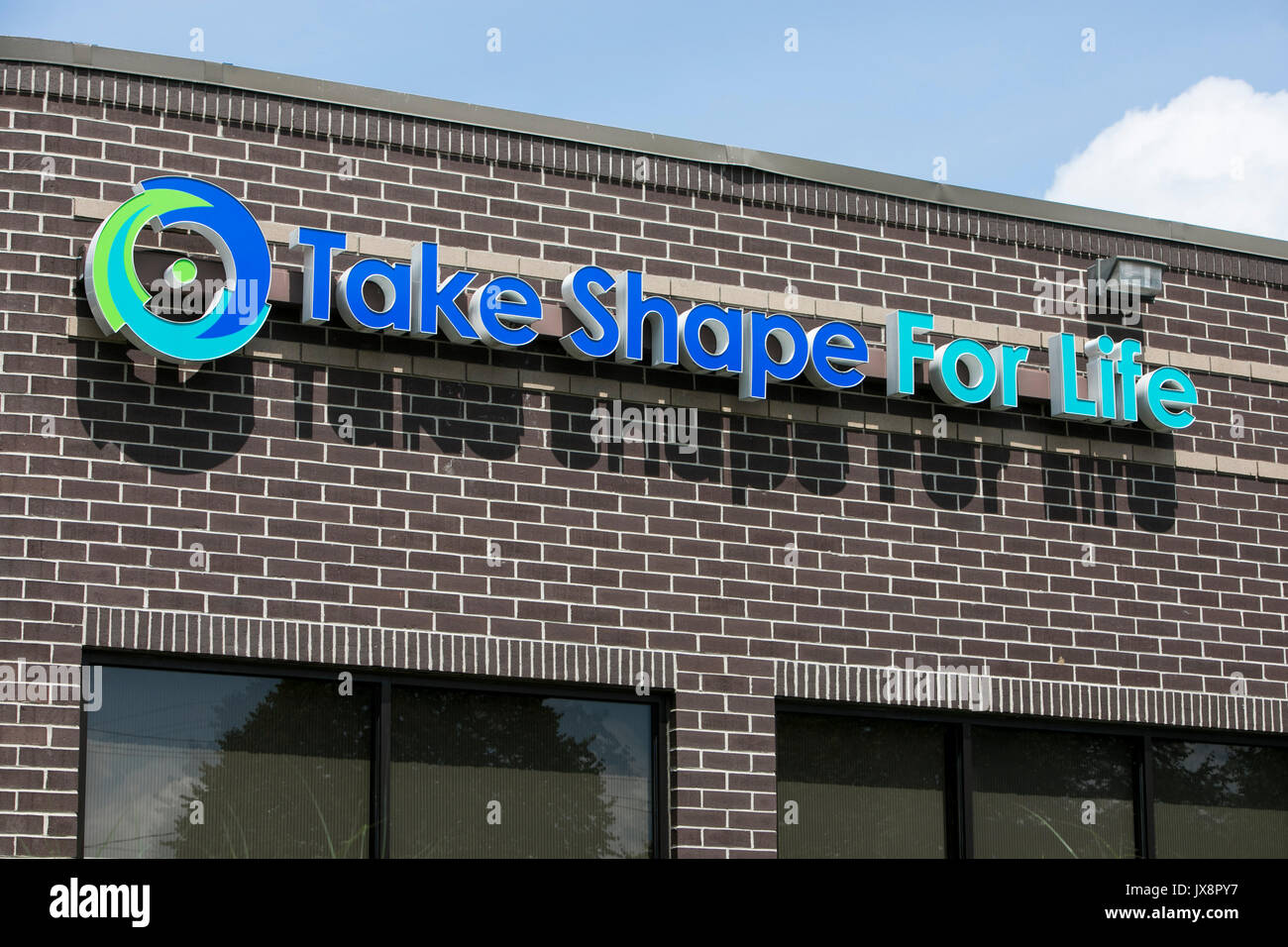 A logo sign outside of a facility occupied by Take Shape For Life, a ...