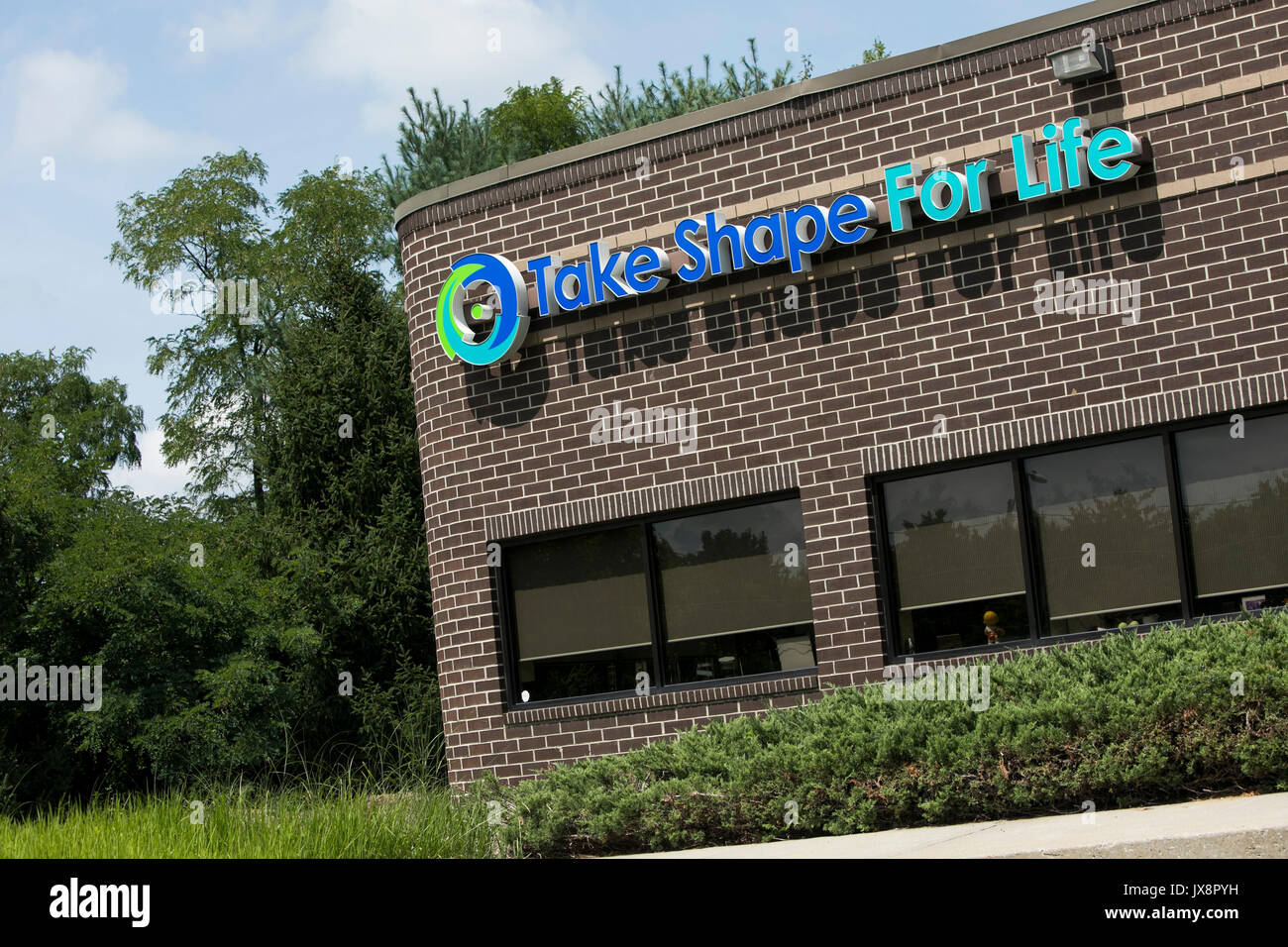 A logo sign outside of a facility occupied by Take Shape For Life, a ...