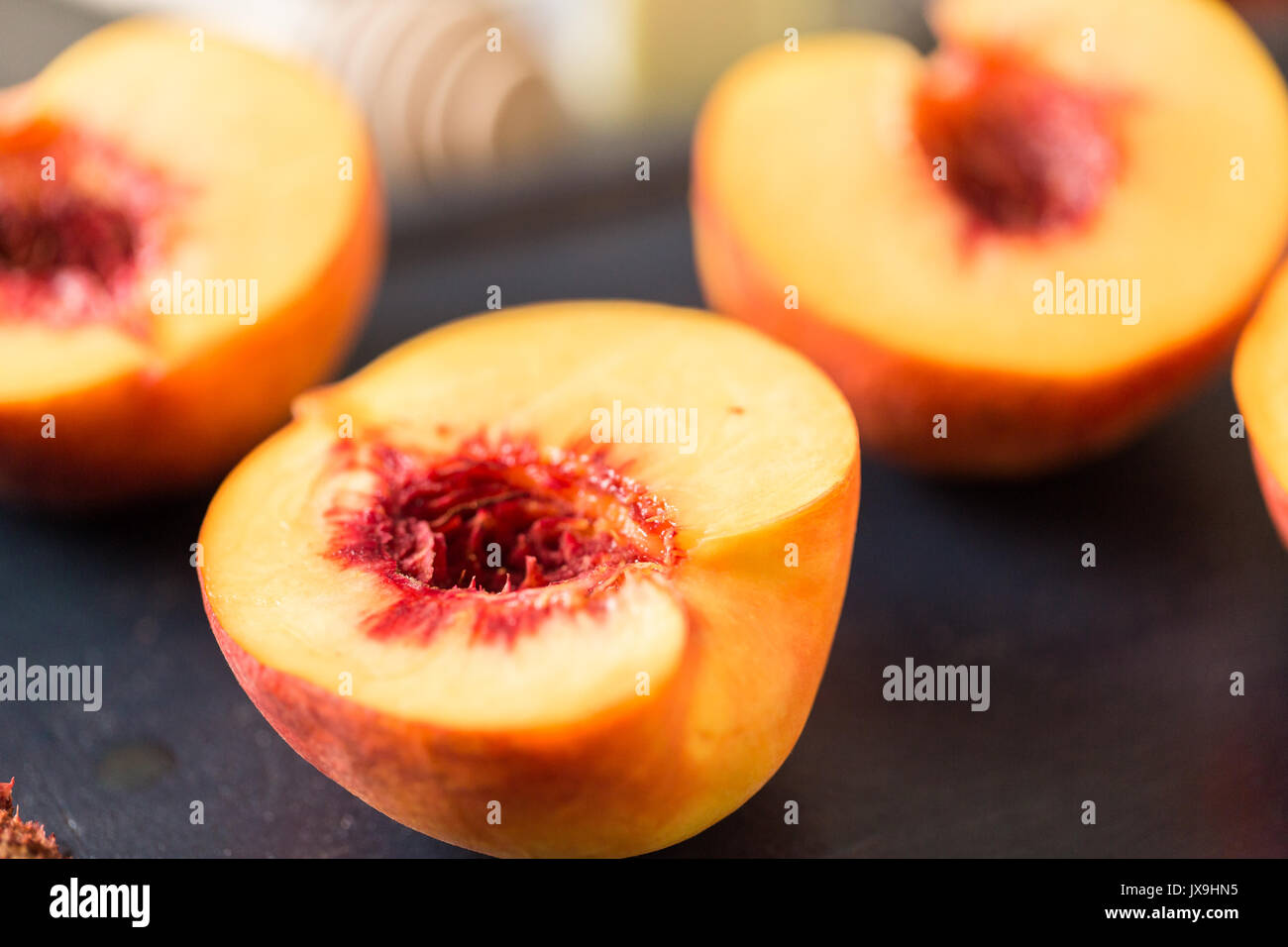 Cutting peaches in half for making grilled peaches Stock Photo - Alamy