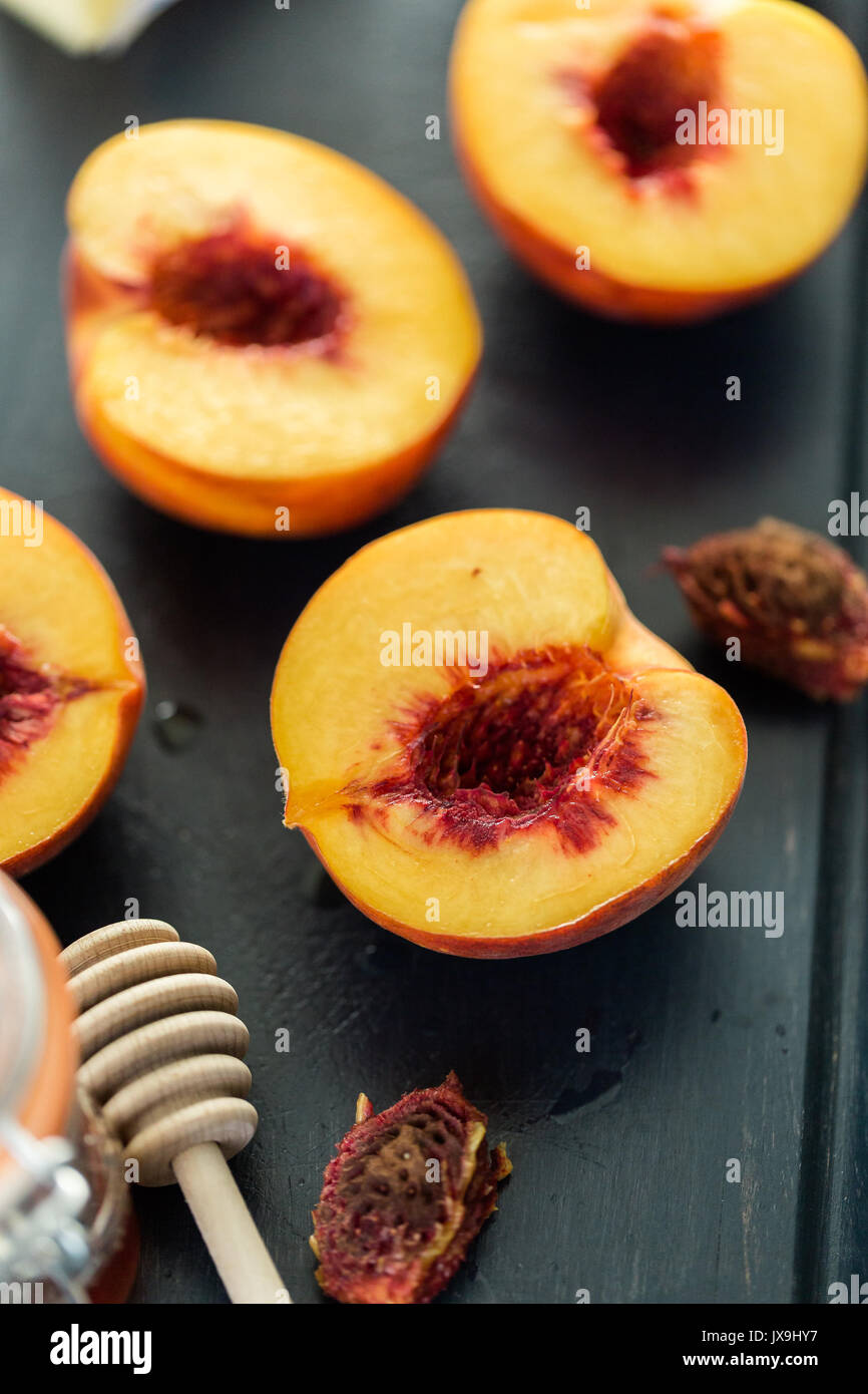 Cutting peaches in half for making grilled peaches Stock Photo - Alamy