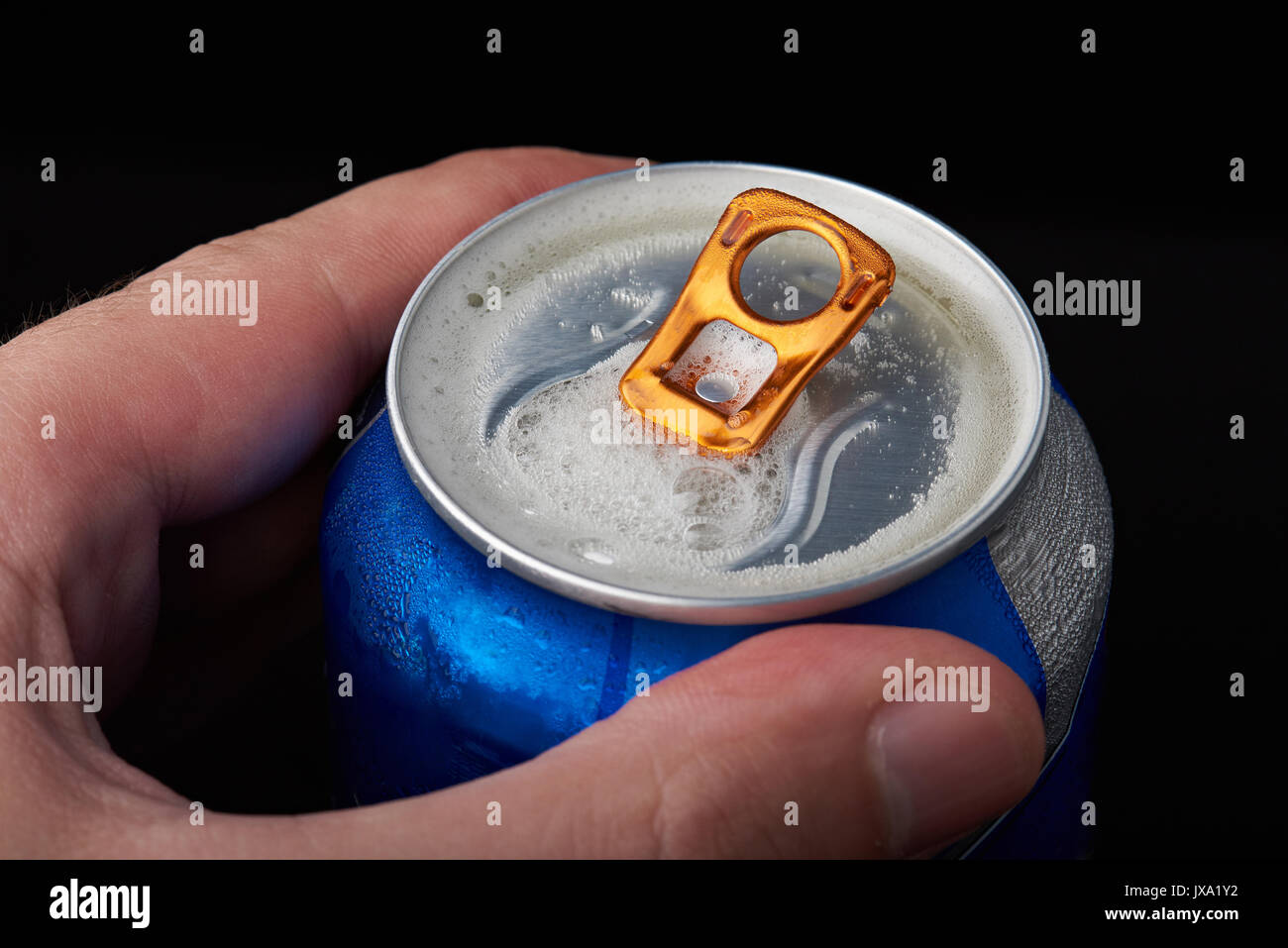 Beer foam in metal tin can on man hand isolated on black background ...