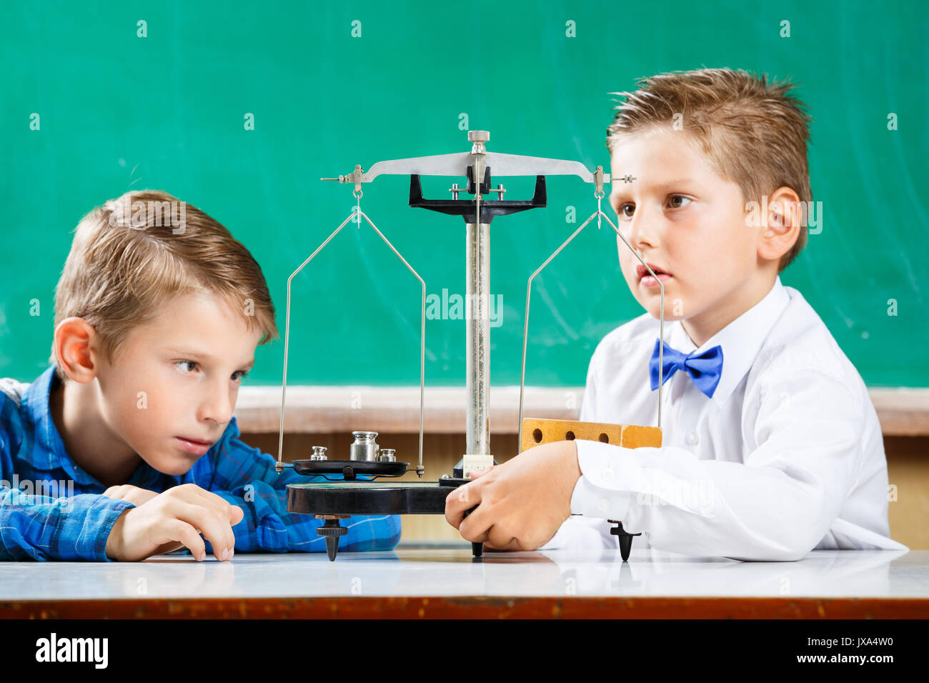 Two small schoolmates use scales on lesson in school Stock Photo - Alamy