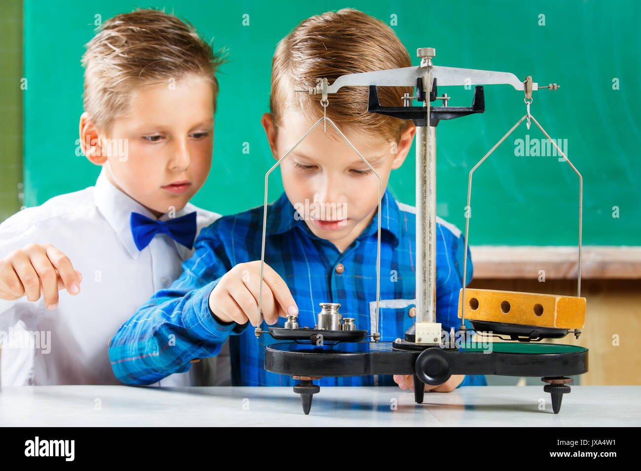 Two small schoolmates use scales on lesson in school Stock Photo - Alamy