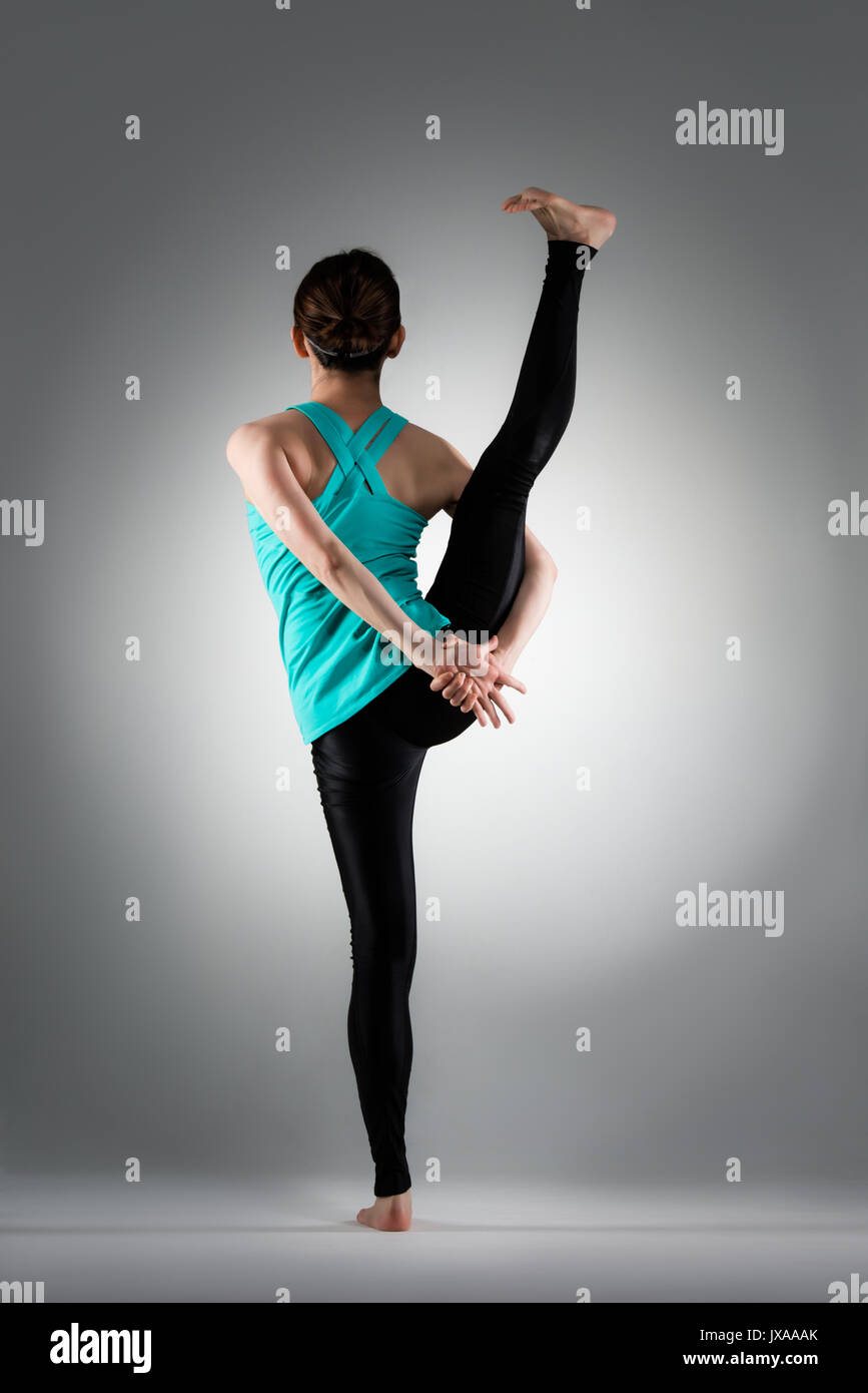 back view photo of young female yoga fitness player using one leg ...