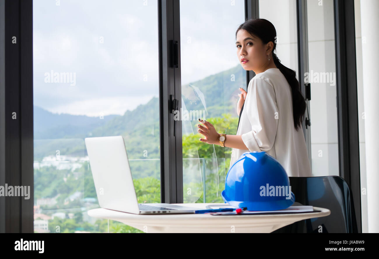 Female engineers standing at windows Engineer hats, laptops and a tool ...