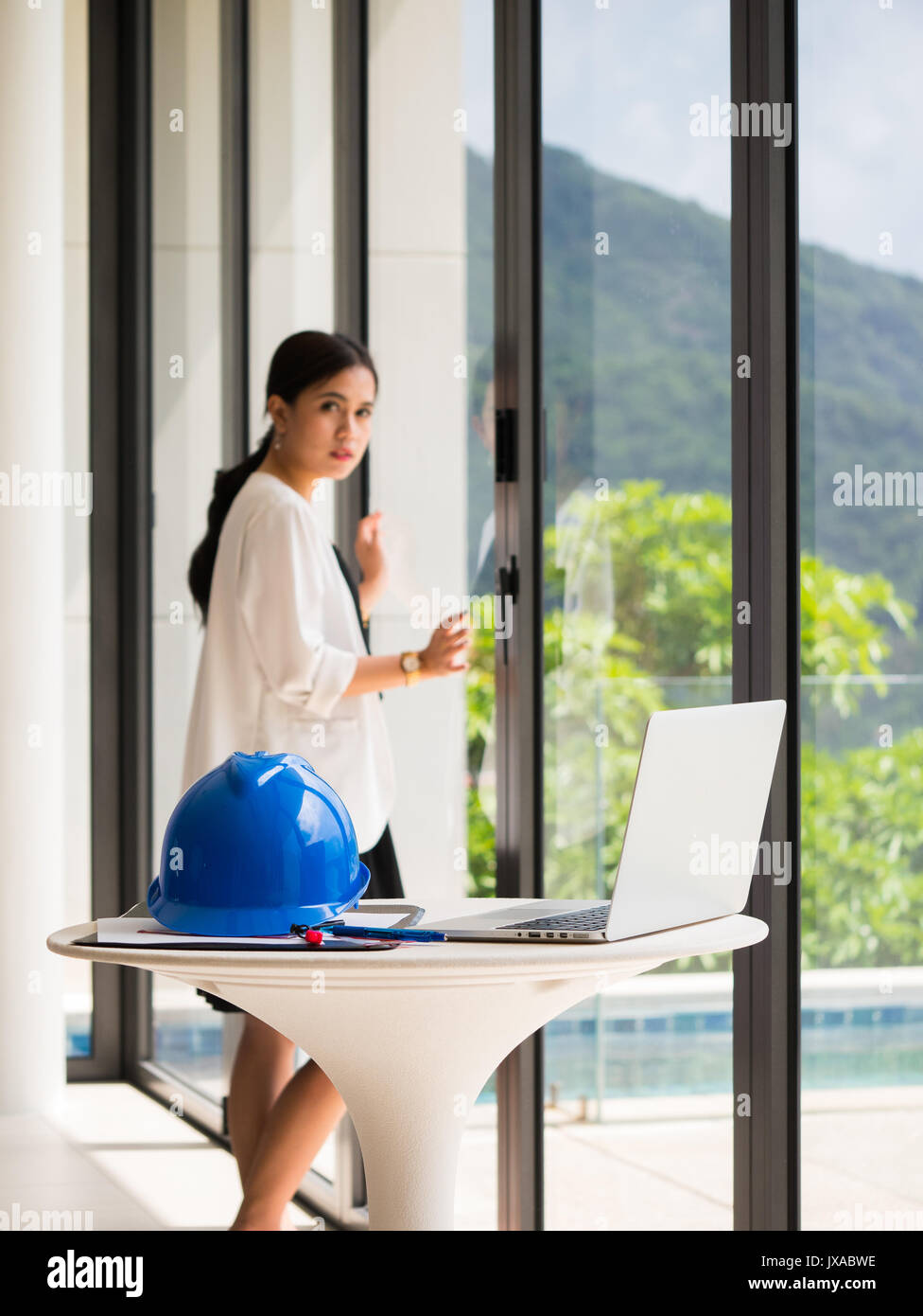 Female engineers standing at windows Engineer hats, laptops and a tool ...