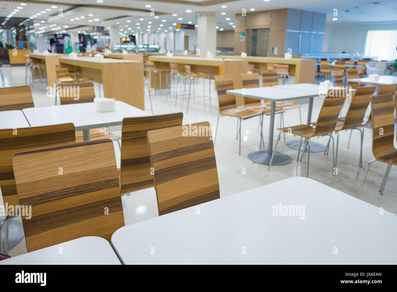 Interior of white table and wooden table on food court in shopping mall ...
