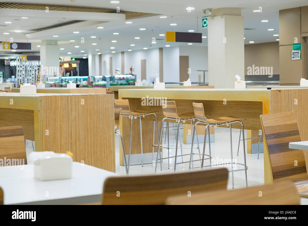 Interior of white table and wooden table on food court in shopping mall ...