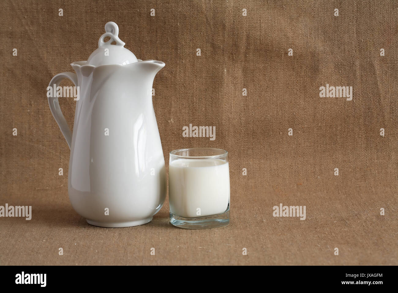 Glass full of milk near pitcher on canvas background Stock Photo - Alamy