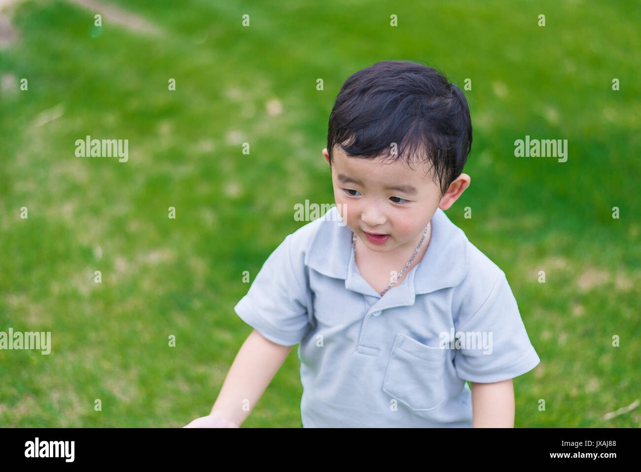 Little Asian kid at the playground under the sunlight in summer ...