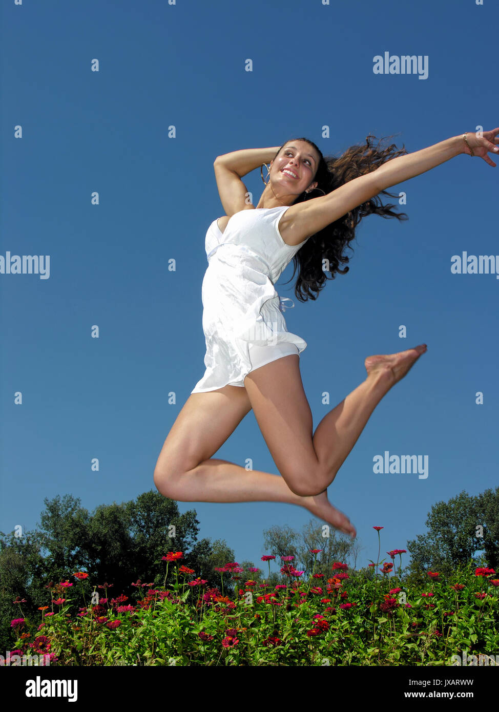 young attractive woman jumping over summer flowers in sunny day Stock ...