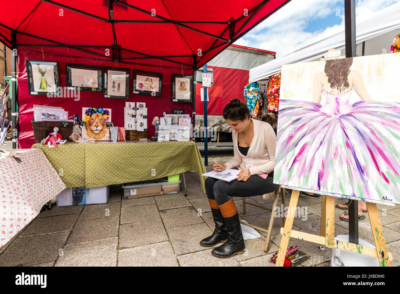 Young Caucasian woman sitting outdoors in front of her market stall ...