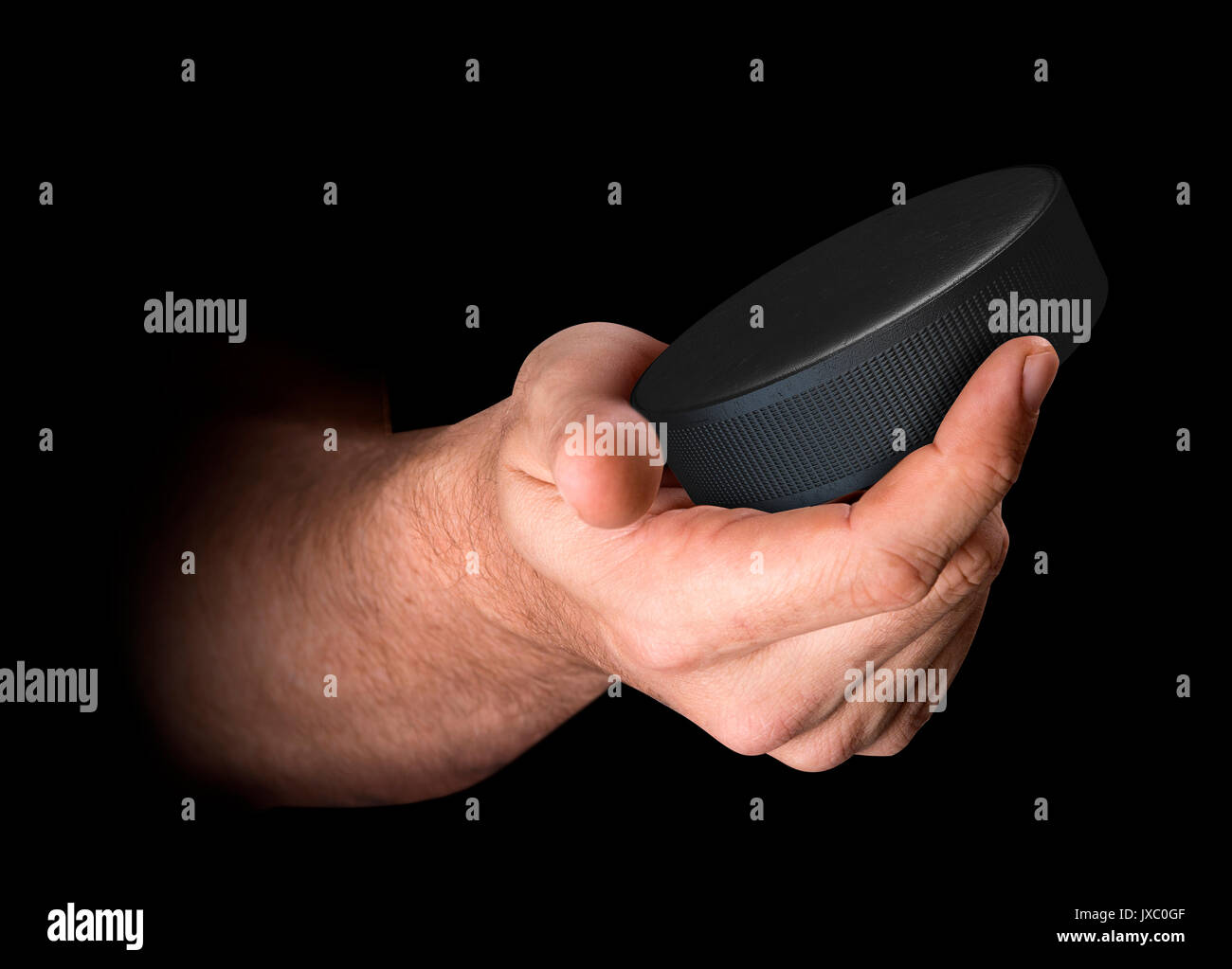 A male hand holding a hockey puck on an isolated dark background - 3D ...