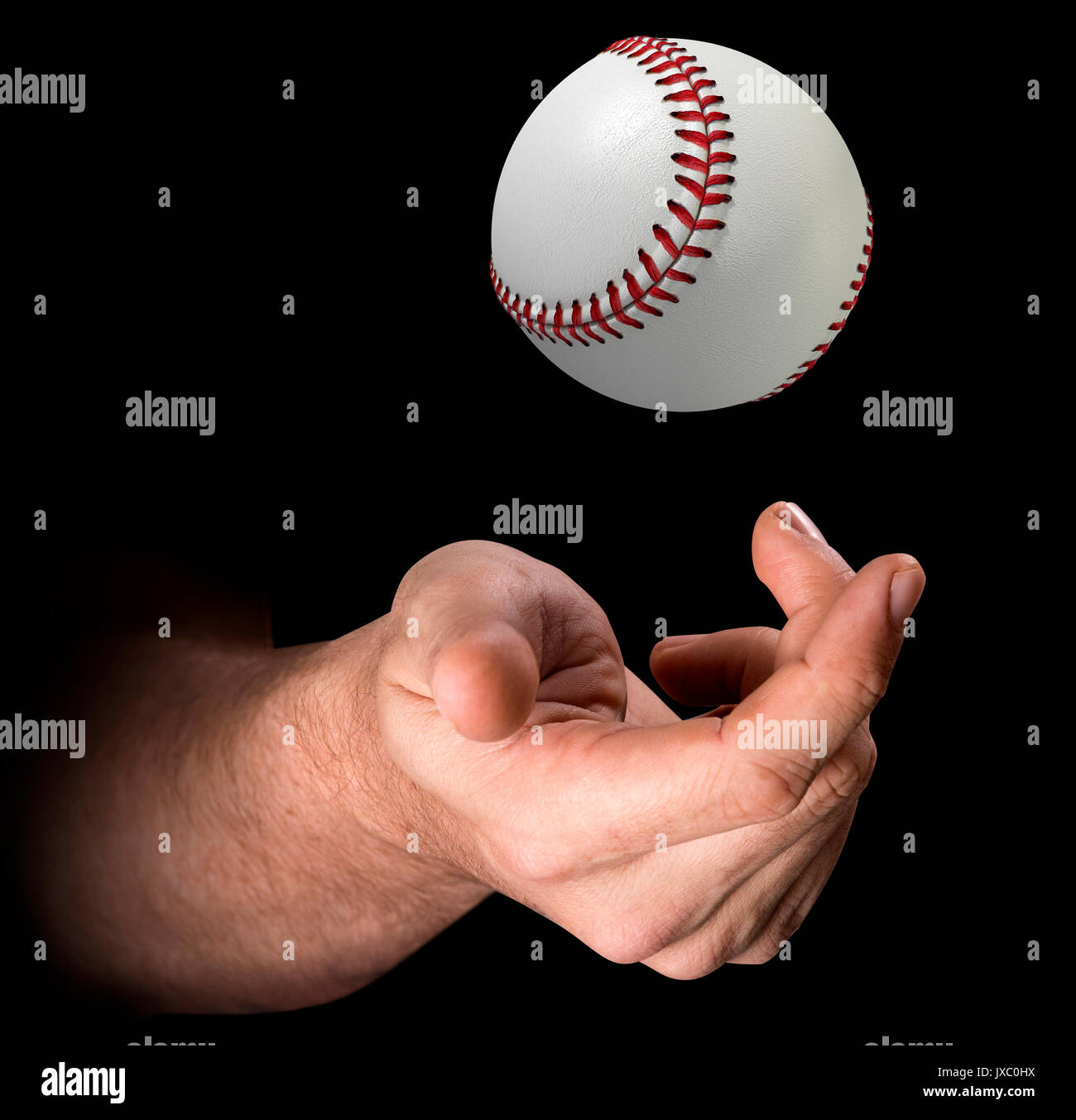 A male hand tossing a baseball up in the air on an isolated dark ...